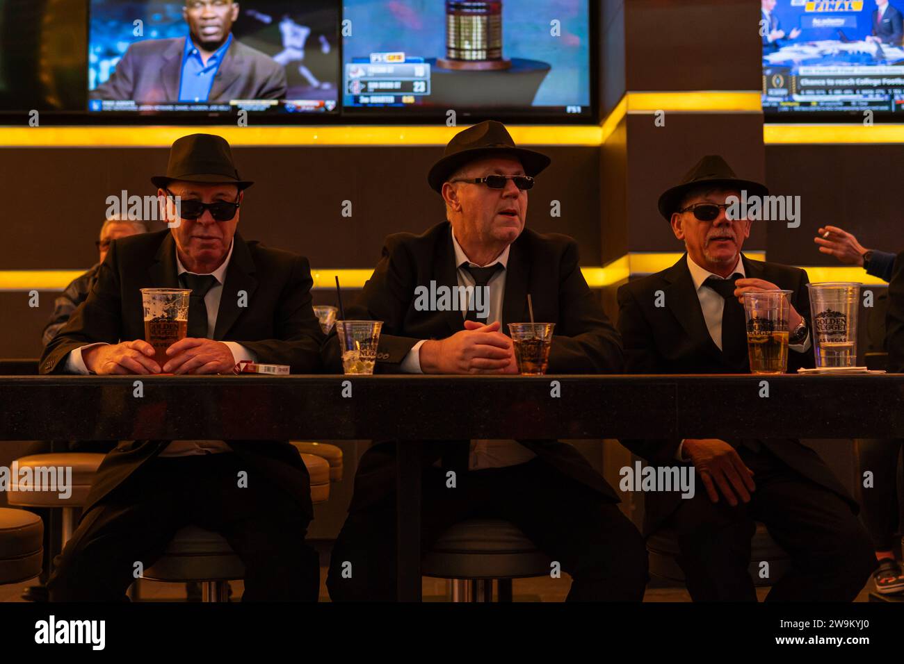 3 men wearing sunglasses, fedora, and a suit sitting at the bar Stock ...