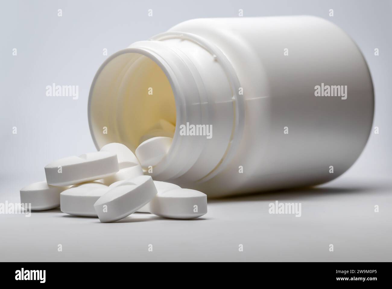 Open pill bottle with pills on a very light background Stock Photo - Alamy