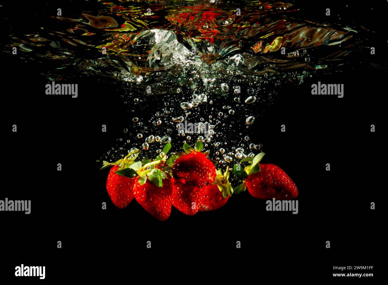 Strawberry Fruit Falling into the water. Splash Drops, Bubbles and Dark ...
