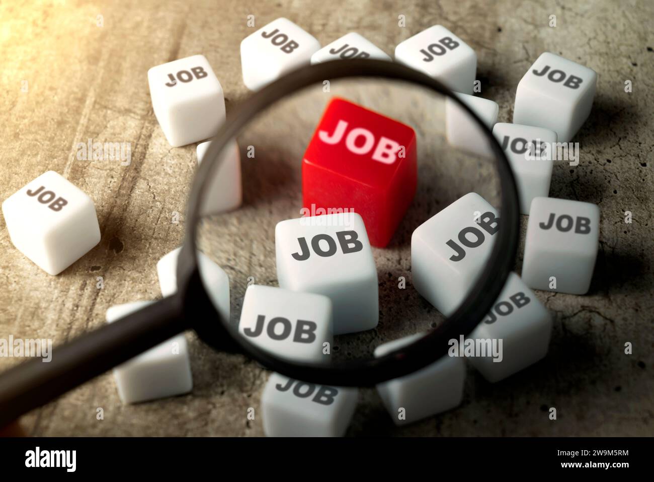 Magnifying glass focuses on small cubes with JOBS letters on the table ...