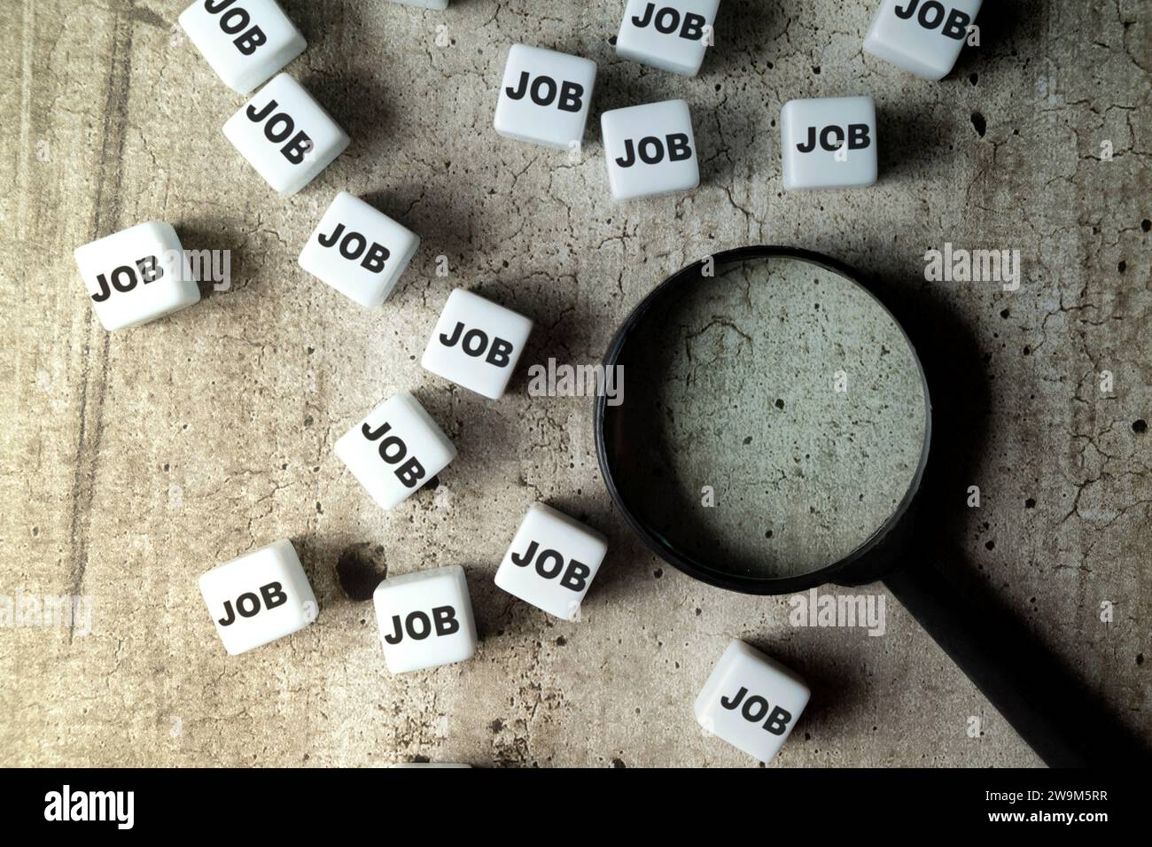 Magnifying glass and a bunch of small cubes with JOBS letters on the ...