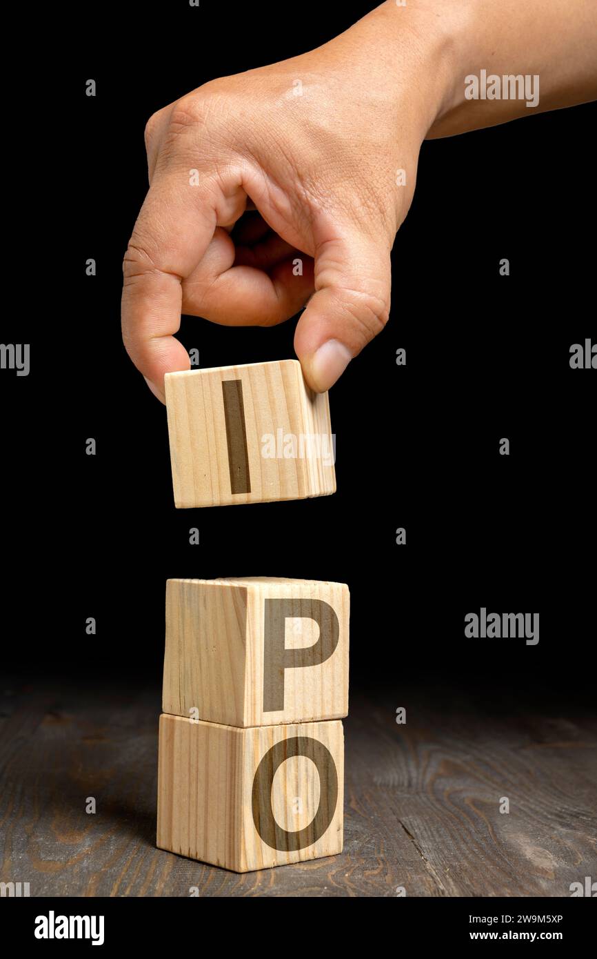 A human hand put a stack of wooden cubes with IPO letters on a wooden ...