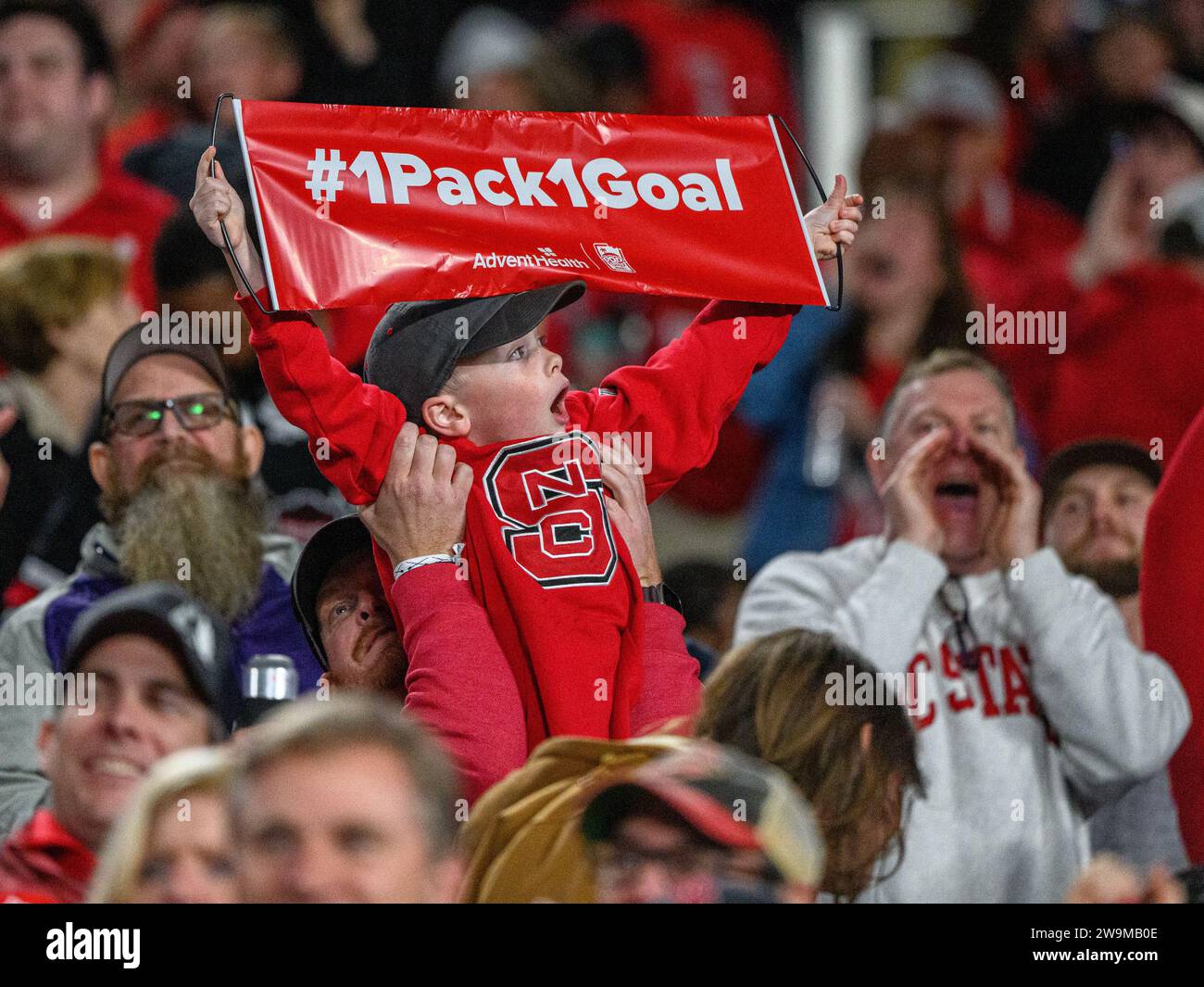 December 28, 2023: A young NC State fan is hoisted with a banner after ...