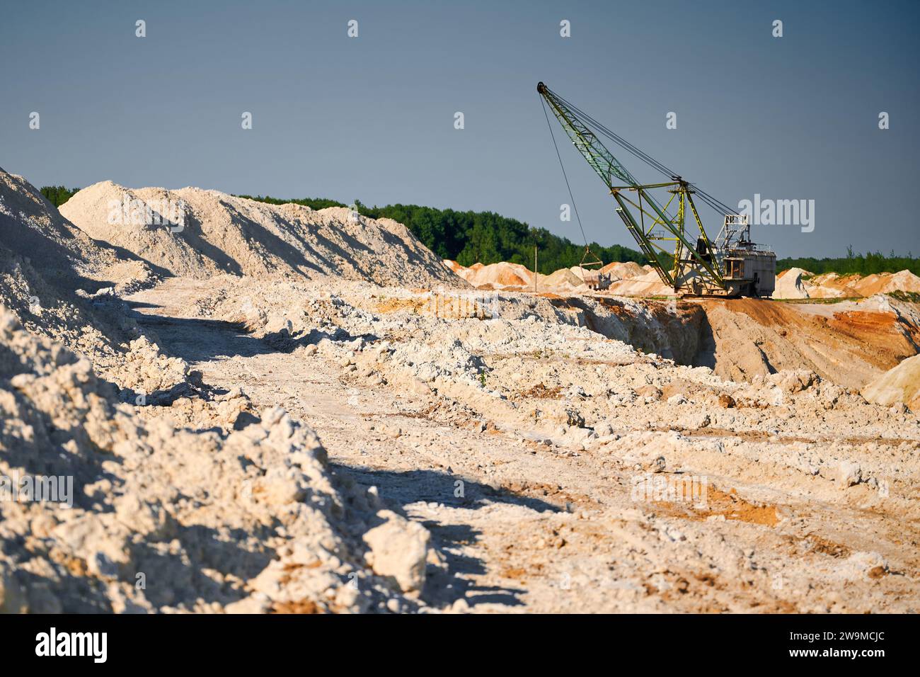 Walking excavator operates in chalk quarry with piles line Stock Photo ...