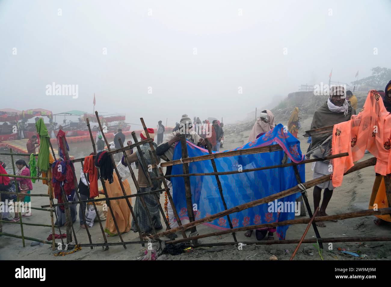 Hindu devotees hang laundry on a bamboo fence after taking a bath in ...