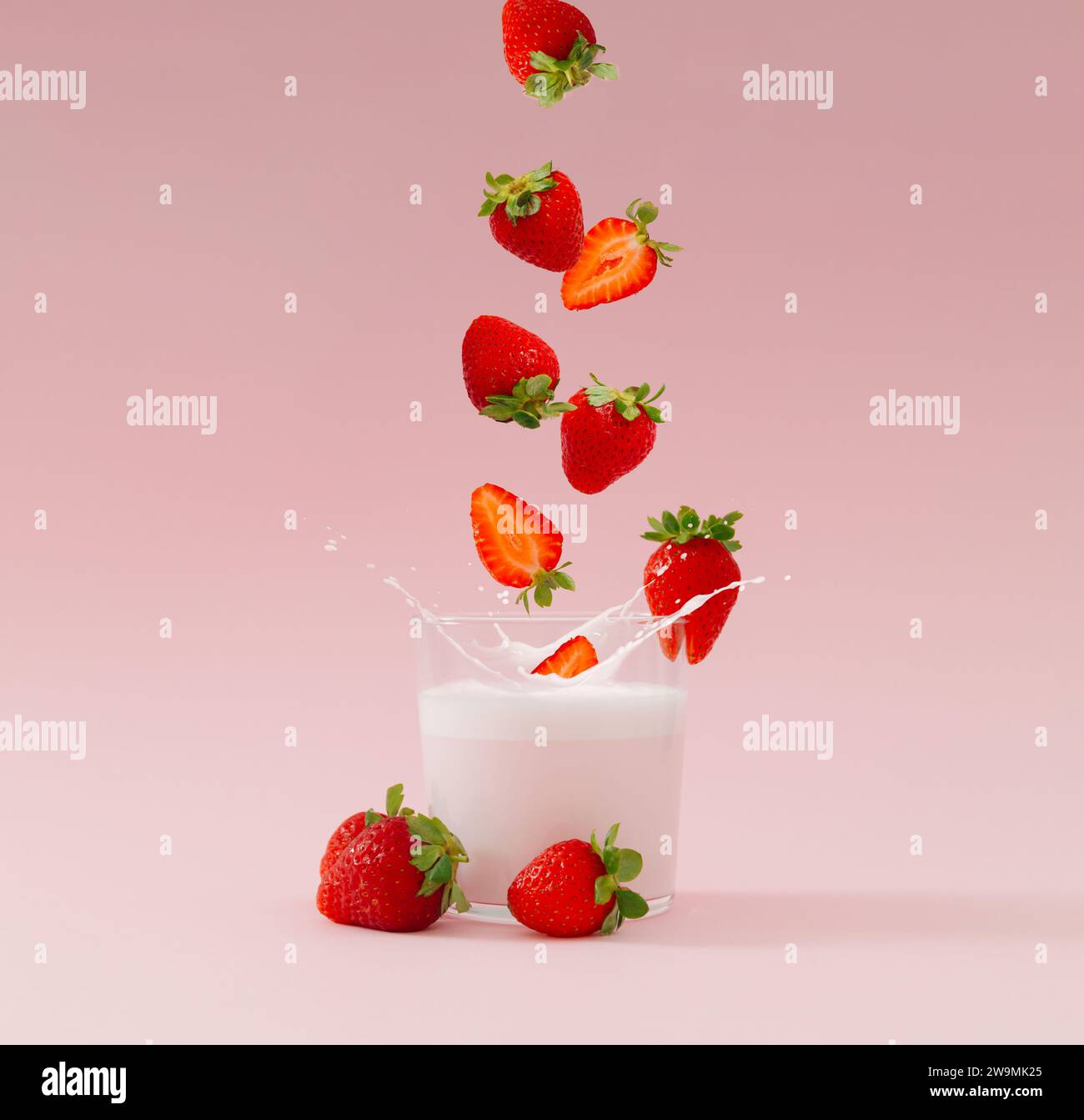 Creative layout made of strawberries falling into glass cup of milk ...