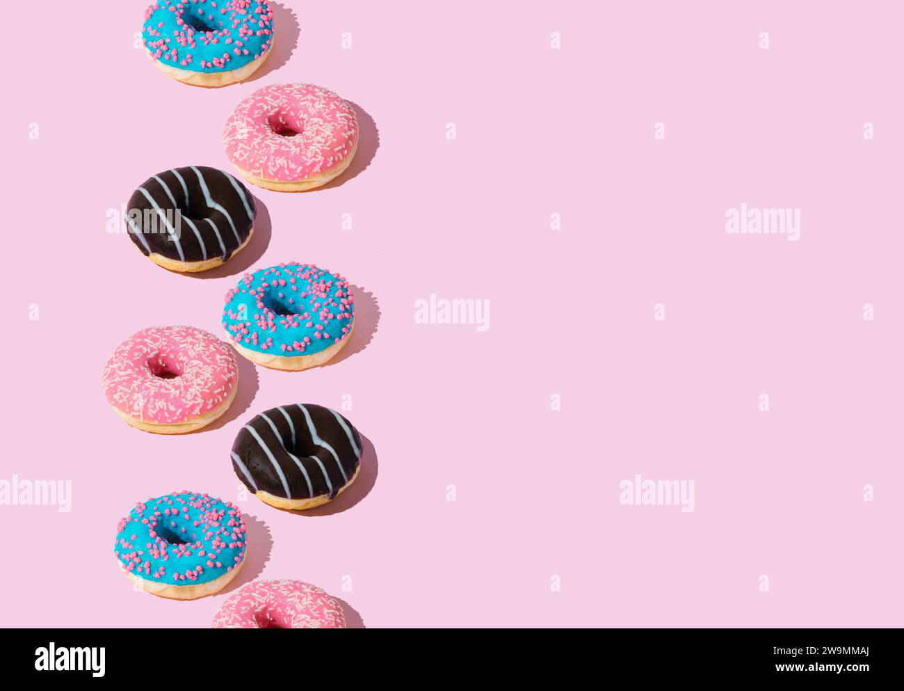 Creative arrangement of colorful donuts on pastel pink background with ...