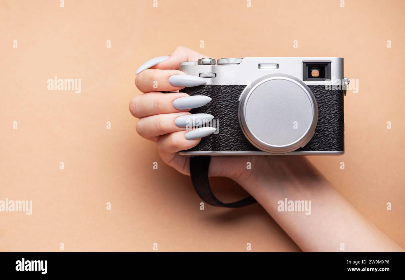 Close up of woman's hand with grey nail polish holding camera Stock ...