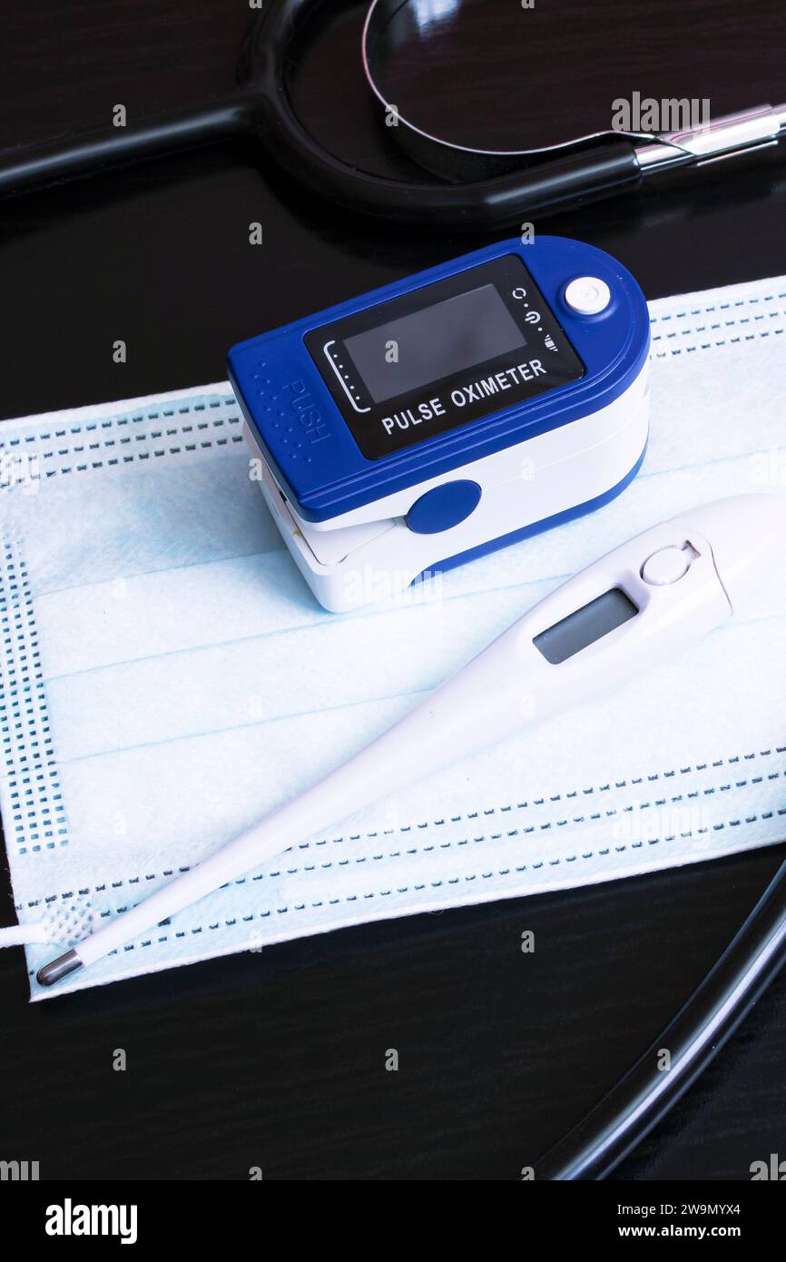 Mask, stethoscope, thermometer and oximeter on black background close ...