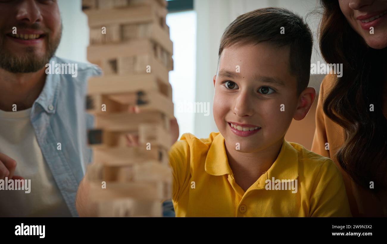 Close-up happy caucasian family mom dad son having fun playing Jenga caring parents play with ...