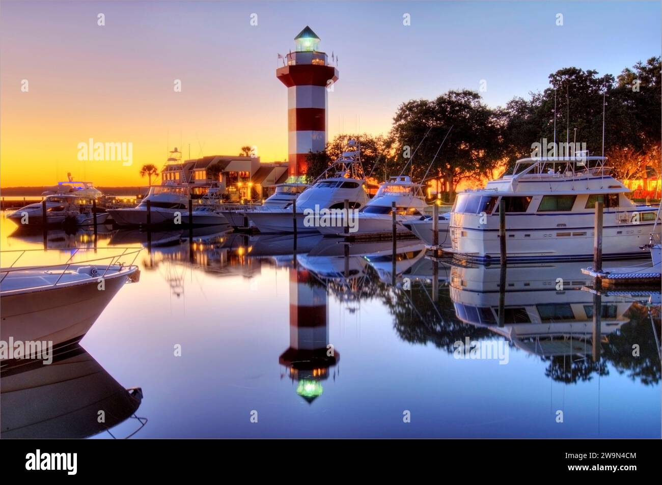 Boats and the lighthouse are reflected in the Harbour Town Marina at ...