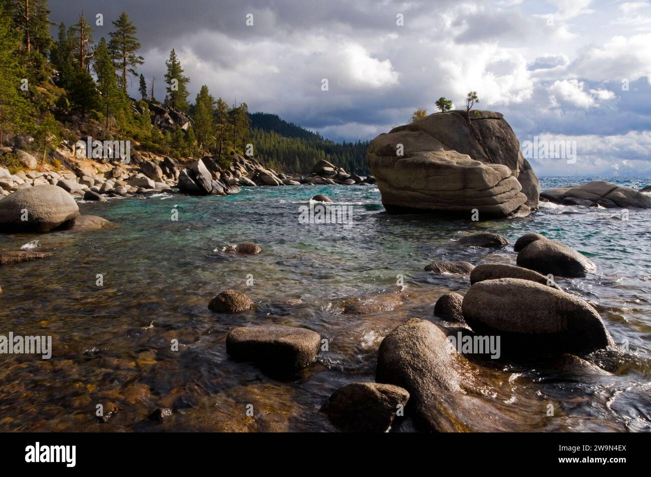 Dramatic clouds and turbulent water surround granite boulders on the ...