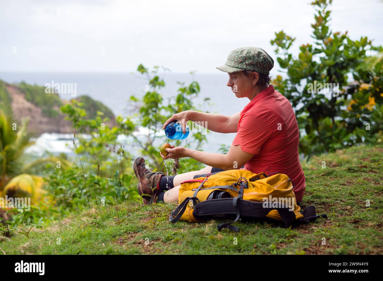 A backpacker washes a fresh picked mango for a snack in the Kalinago ...