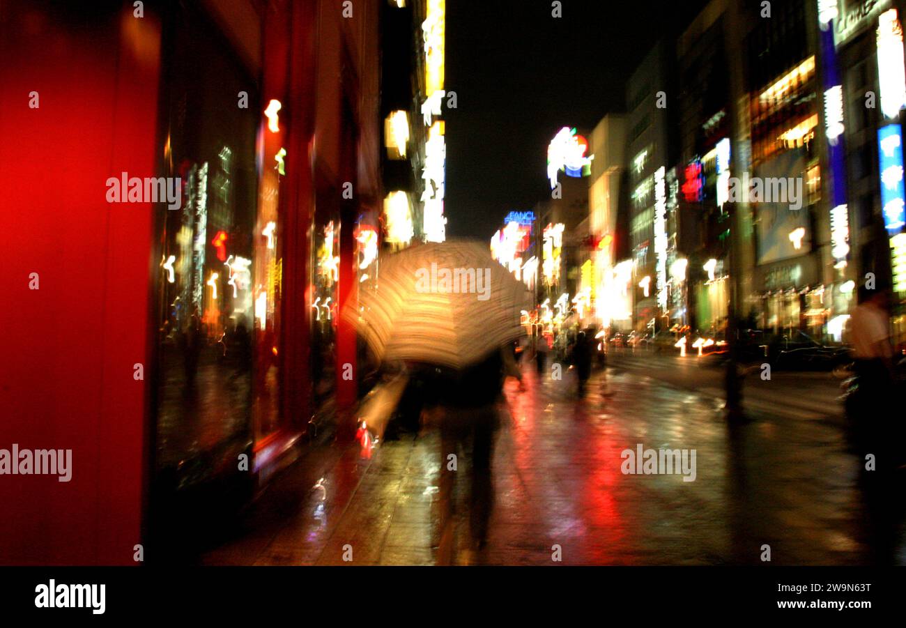 A woman walks through the wet streets of Tokyo with an umbrella at ...