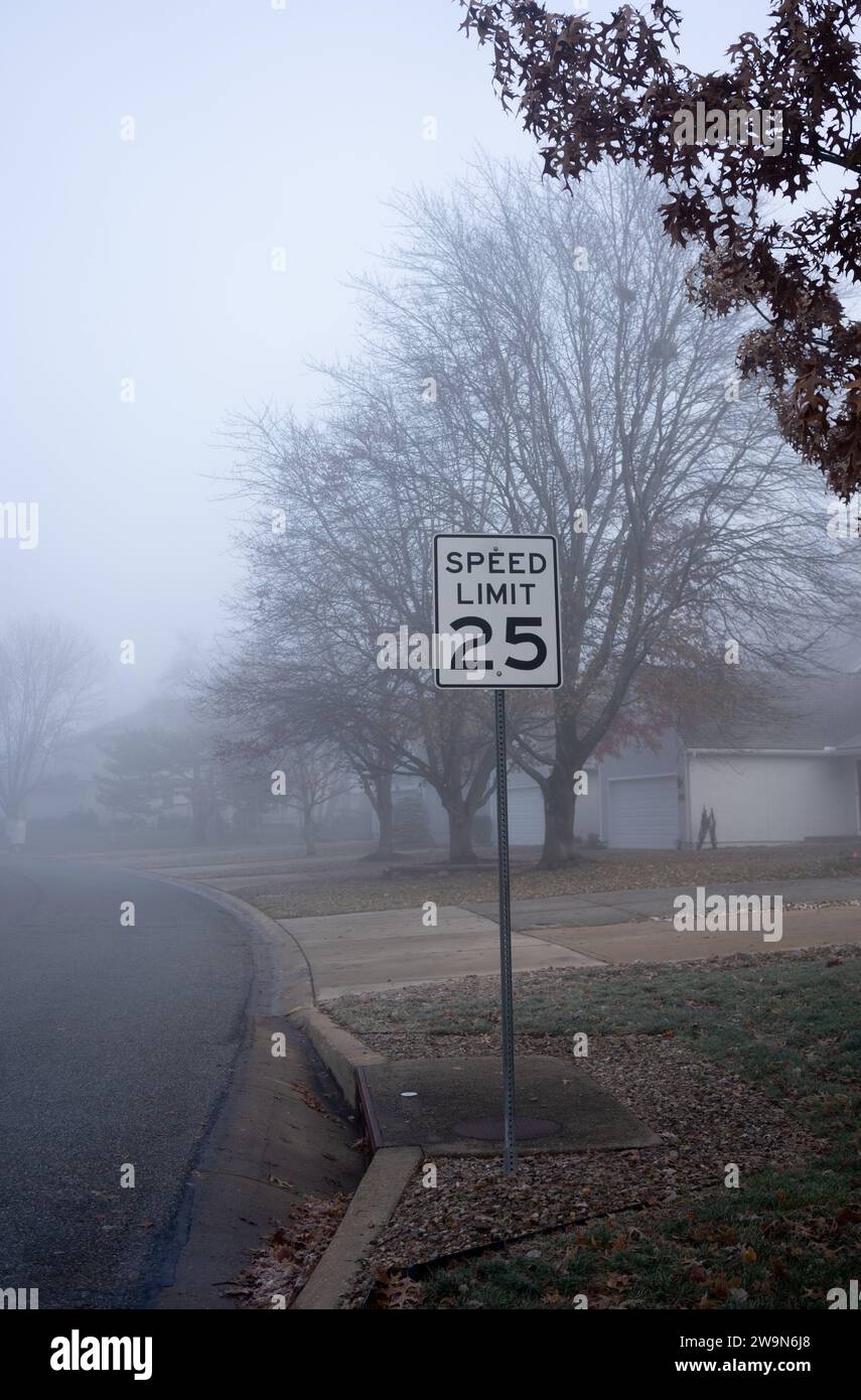 Speed limit sign by road in a neighborhood on a foggy fall morning ...