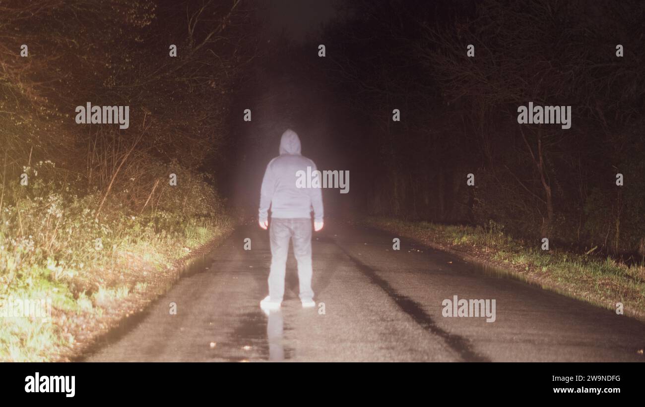 A spooky horror concept of a hooded man, standing in the middle of a ...