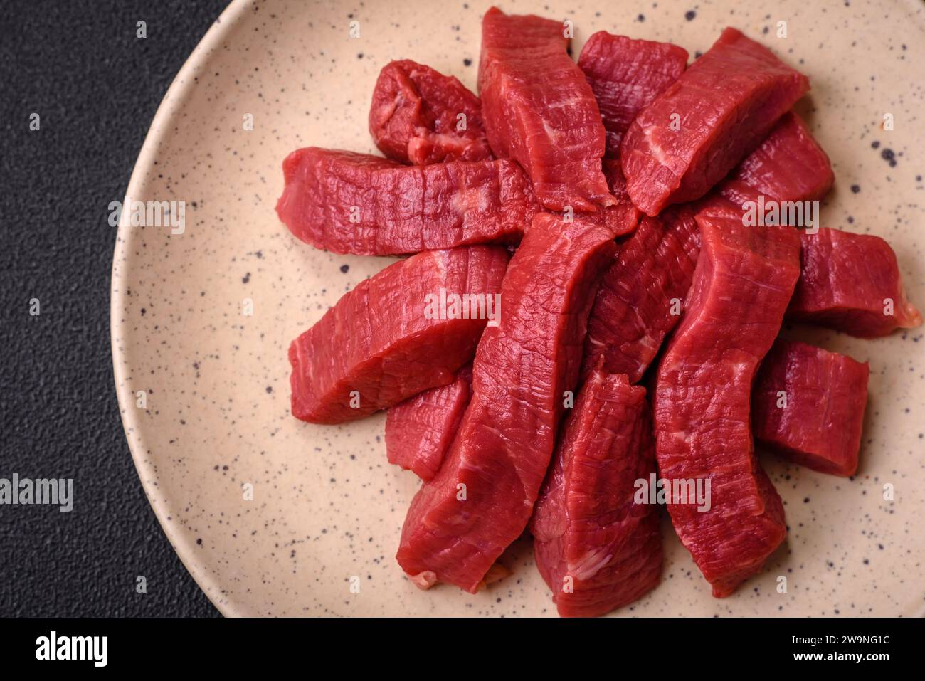 Juicy fresh raw beef meat with salt, spices and herbs on a dark ...