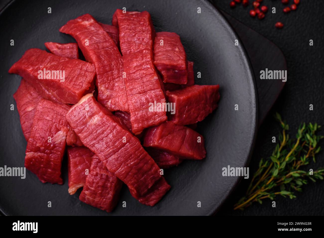 Juicy fresh raw beef meat with salt, spices and herbs on a dark ...