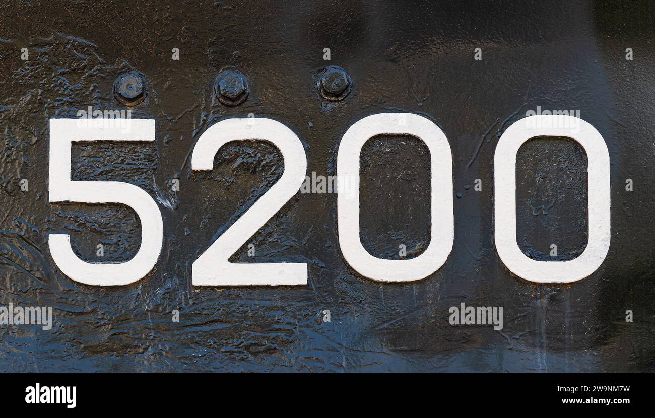 Weathered numbers zero, two, five, 5200, or 5, 2, 0 painted white on a ...