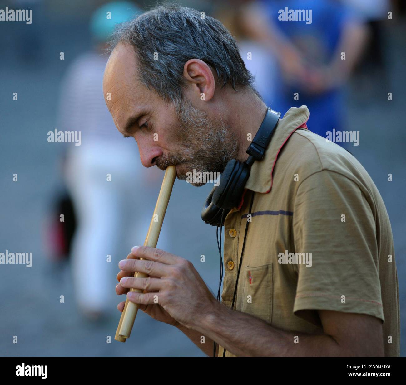 Sad man street musician playing two reed pipes at the same time, people ...