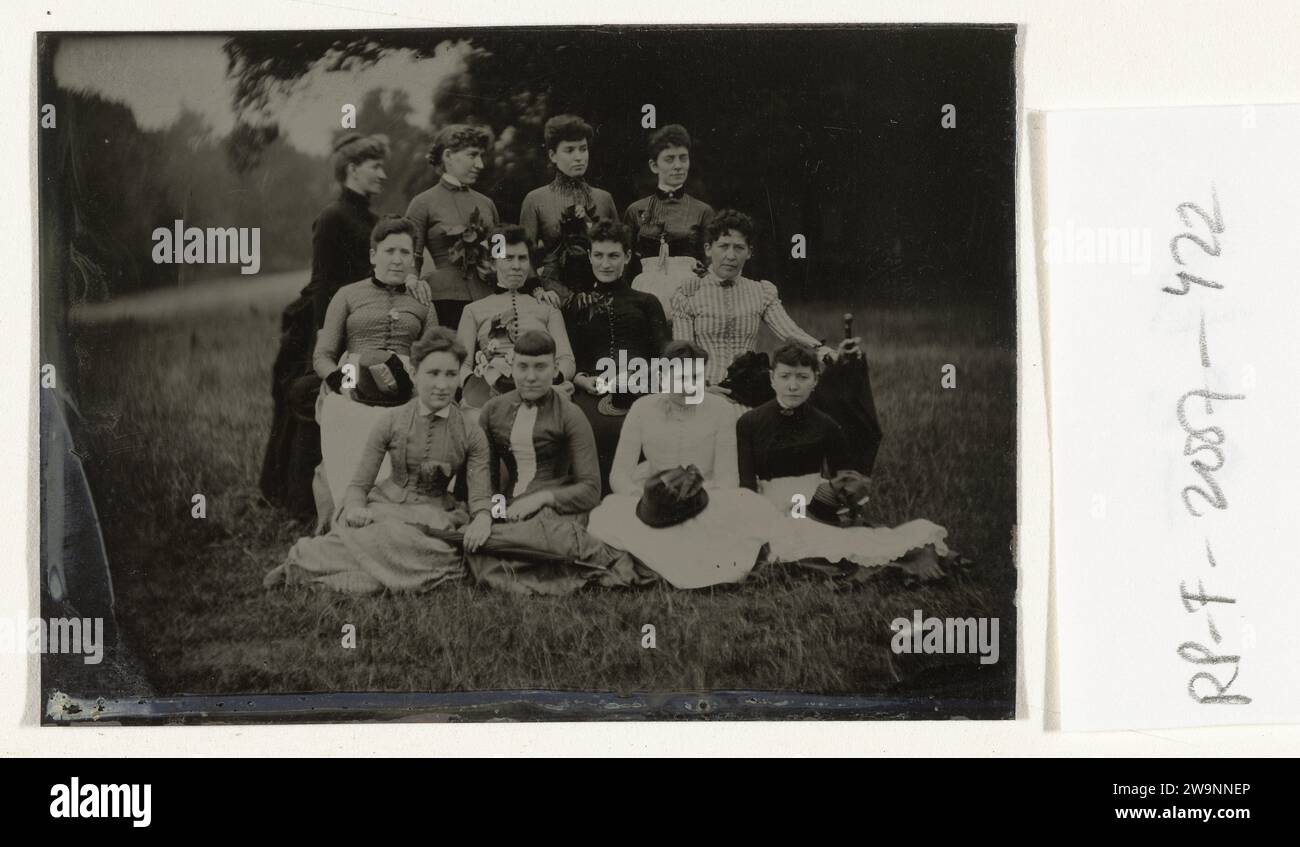 Group portrait of twelve women, standing and sitting in a park -like ...