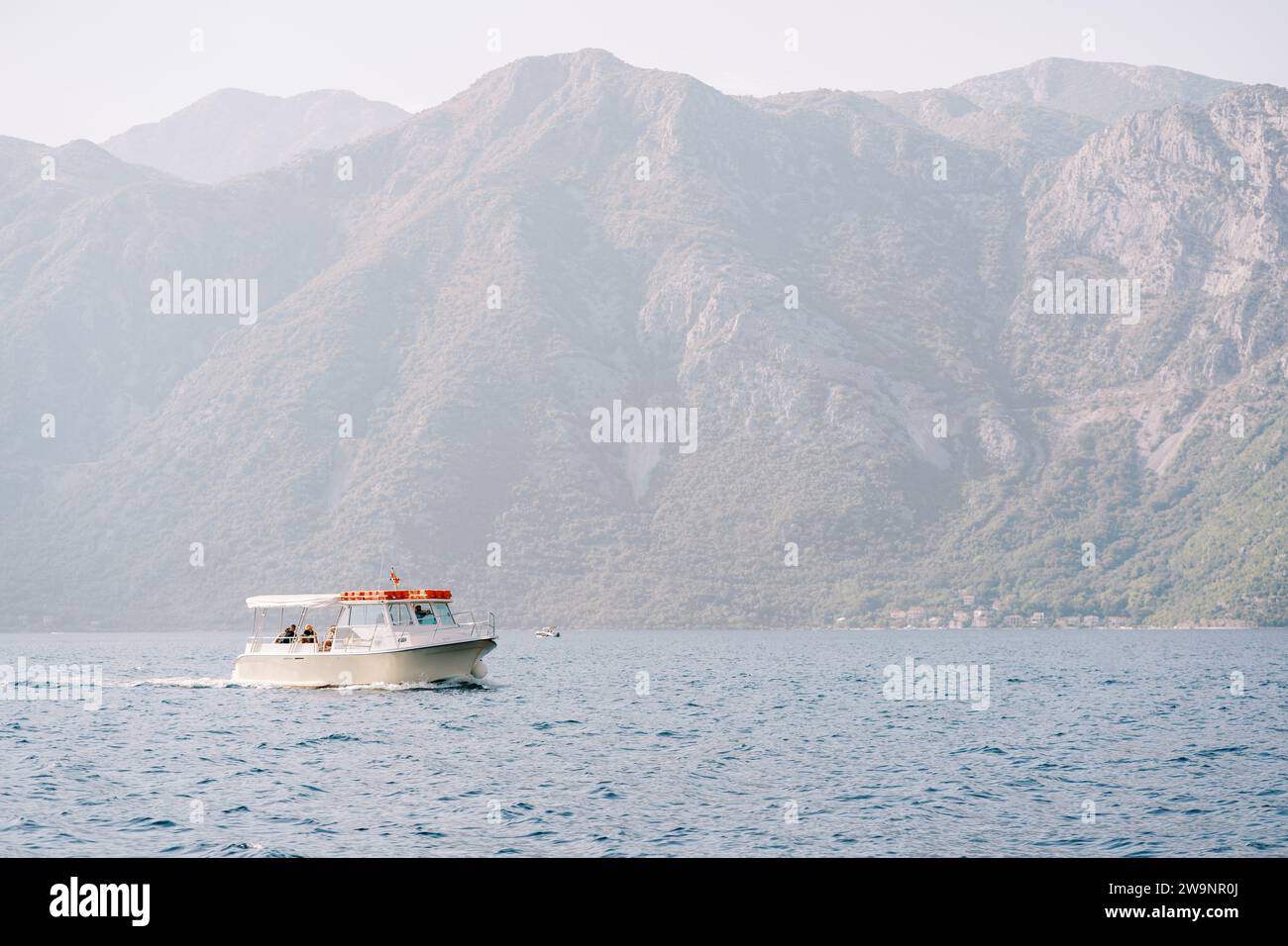 Excursion boat with a cover sails along the sea along the mountains in ...