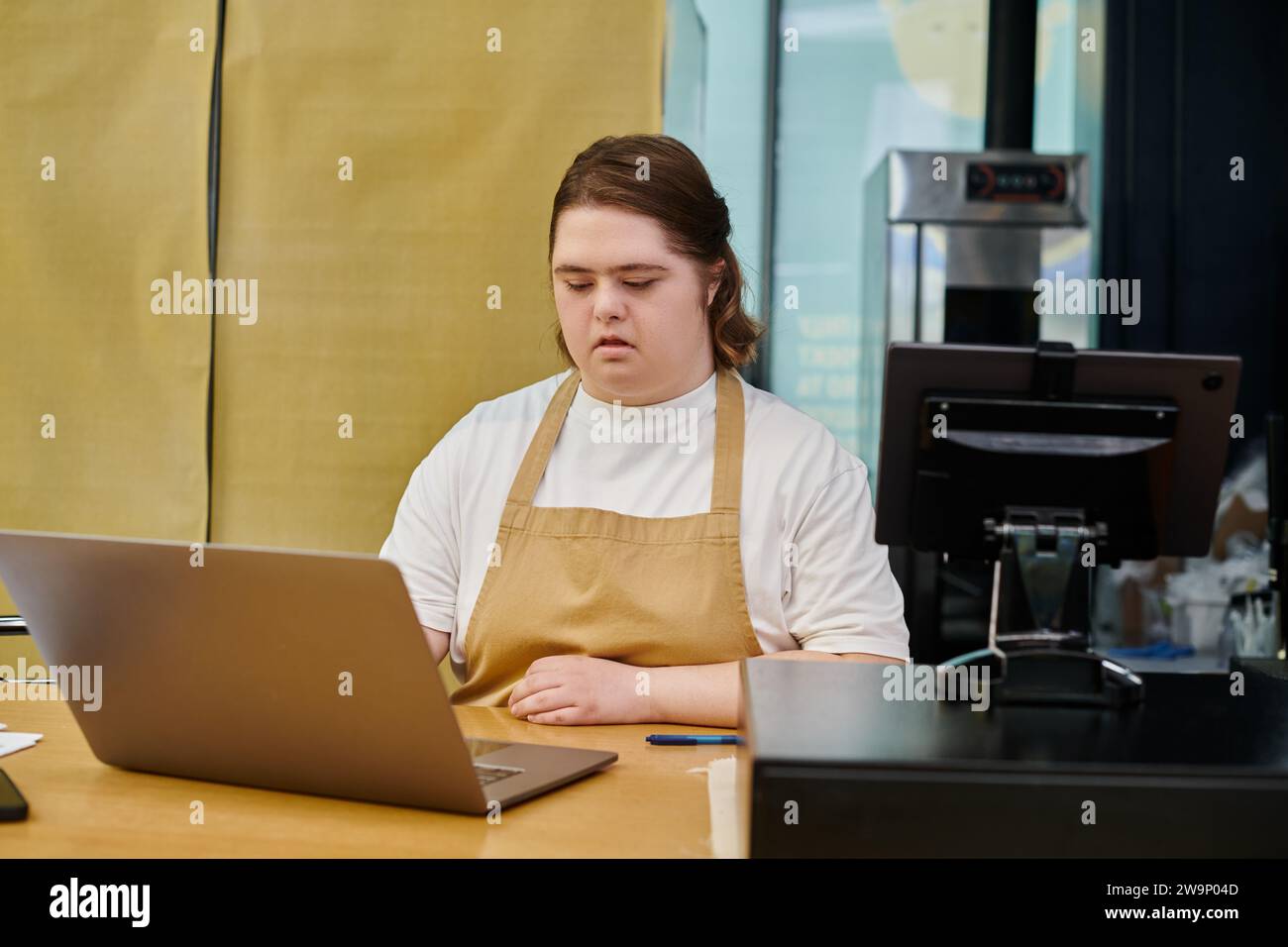 young female employee with mental disorder working on laptop near cash ...