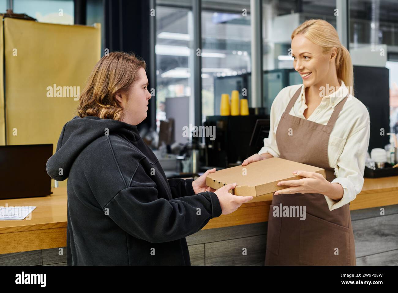 cheerful female manager giving pizza box to young woman employee with ...