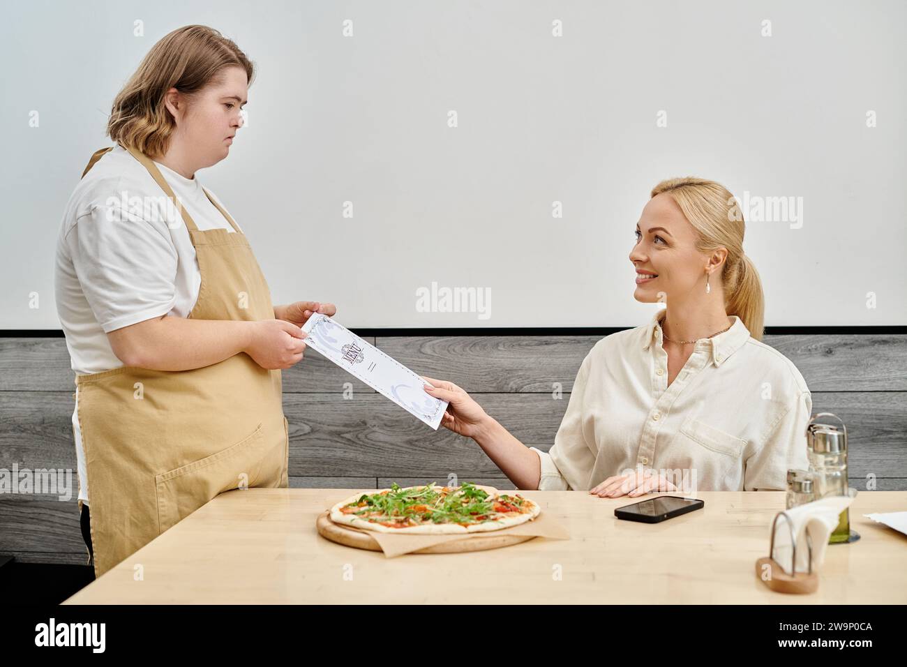 young waitress with mental disability giving menu card to happy woman ...
