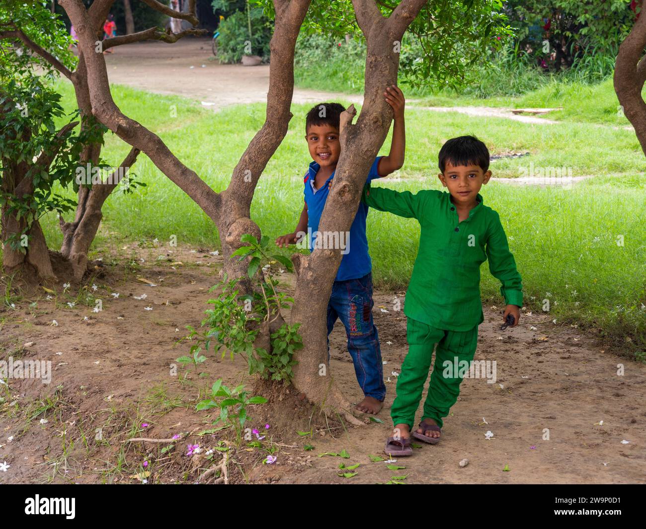 Two young Indian children around trees smiling. Lucknow, Uttar Pradesh ...