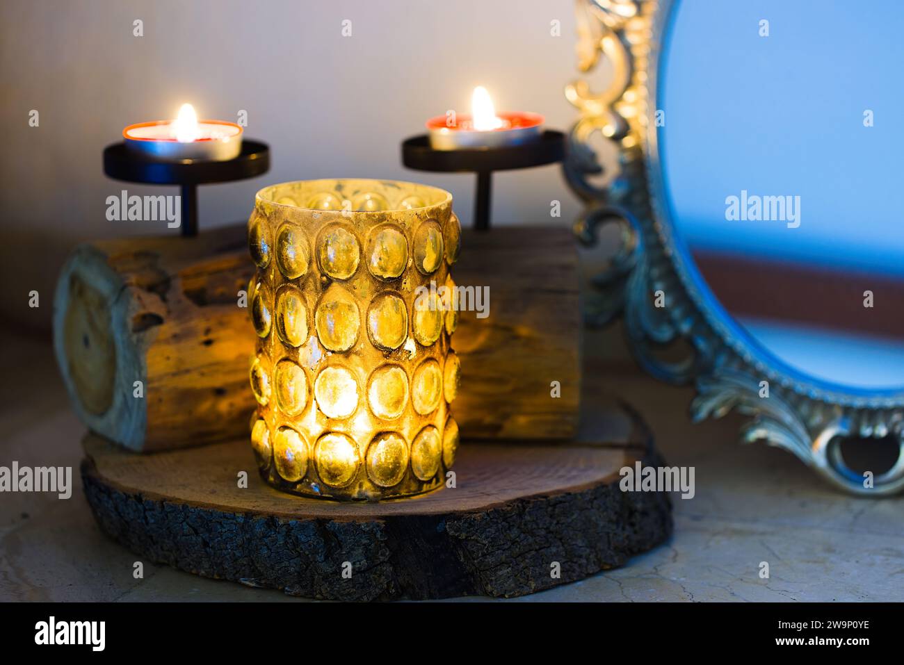 A single candle in a glass cloche and two on wooden candle holders ...