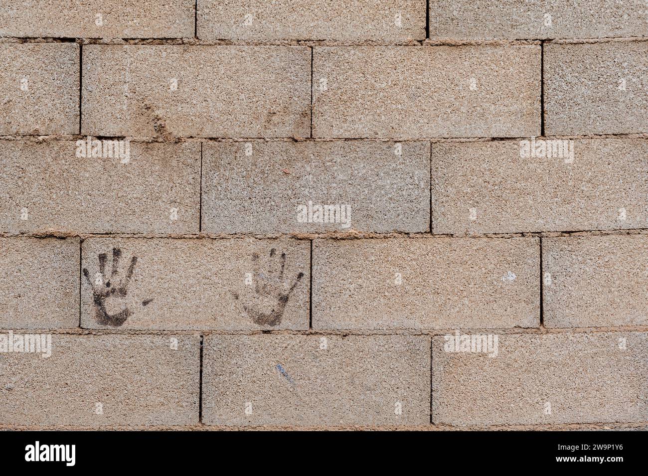 Two black handprints on a sandy concrete brick wall, leaving a human ...