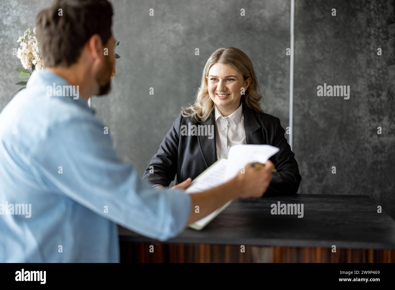 Medical receptionist with man at the reception desk Stock Photo - Alamy