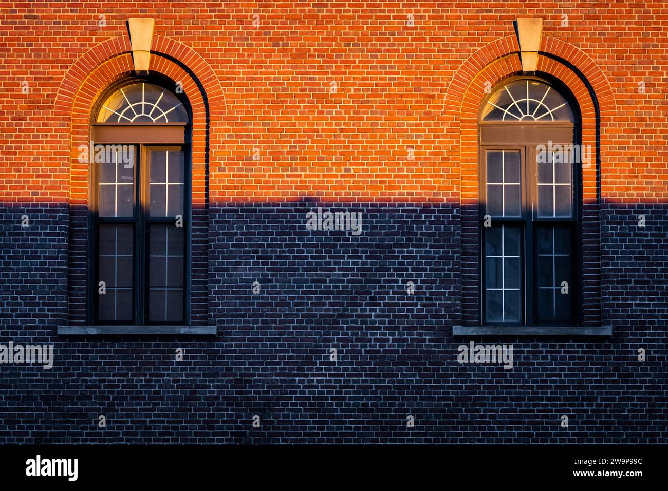 Windows in a brick building just after sunrise appear to mirror the ...
