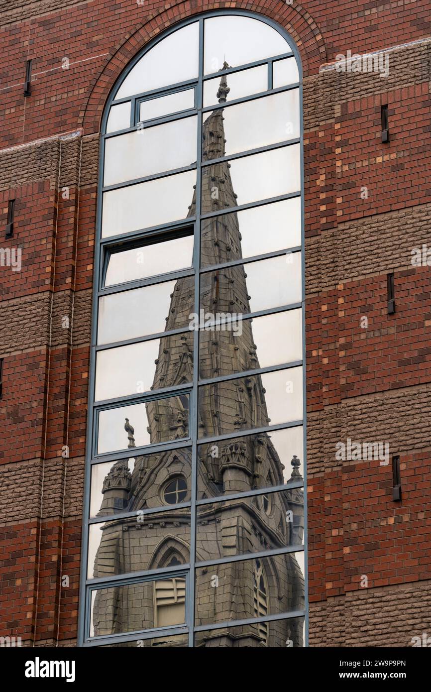 Church steeple reflects on a tall arched window of a brick building in ...