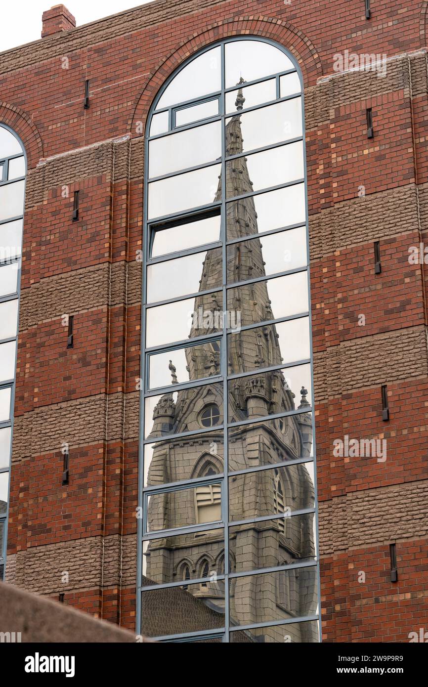 Church steeple reflects on a tall arched window of a brick building in ...