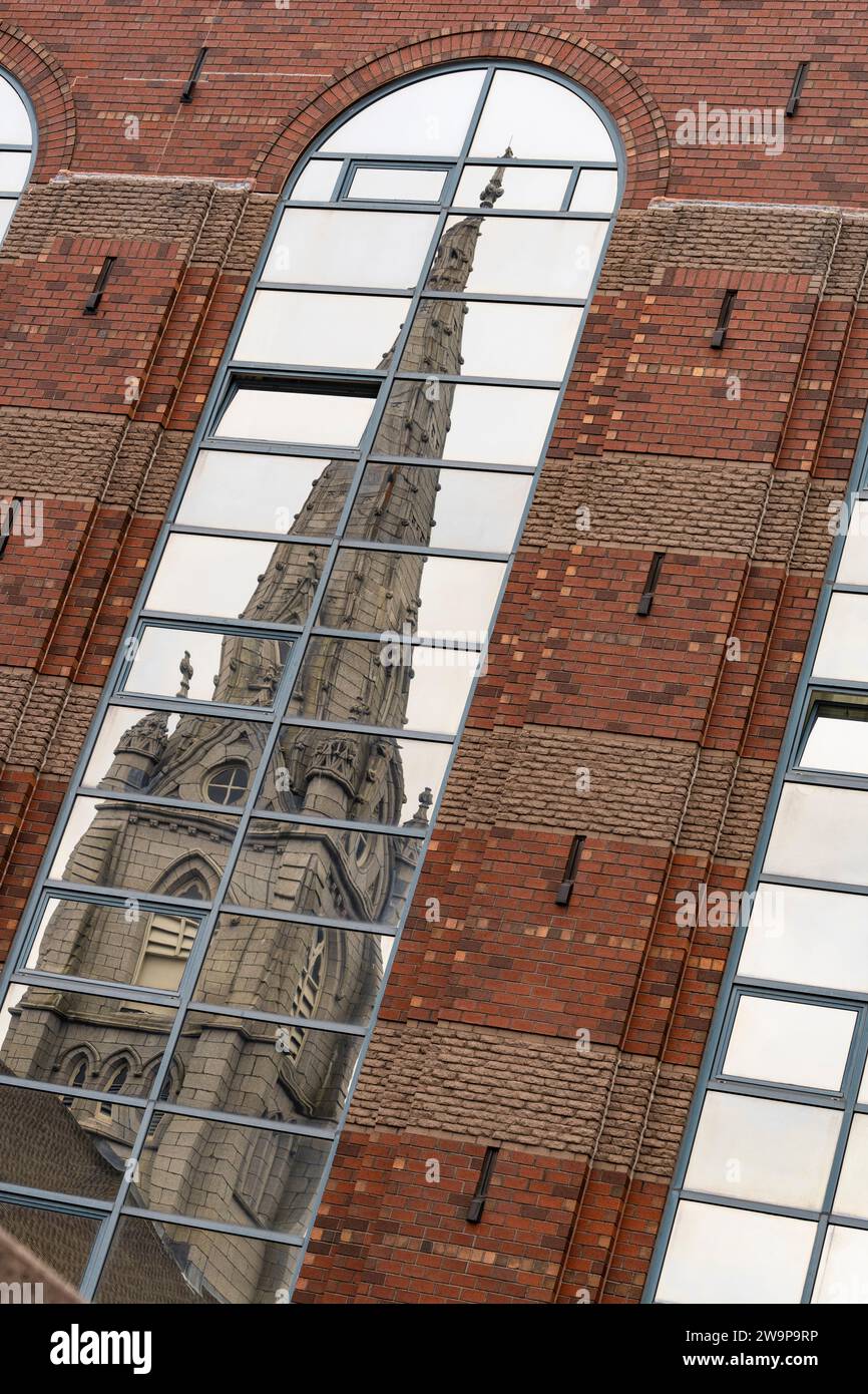 Church steeple reflects on a tall arched window of a brick building in ...