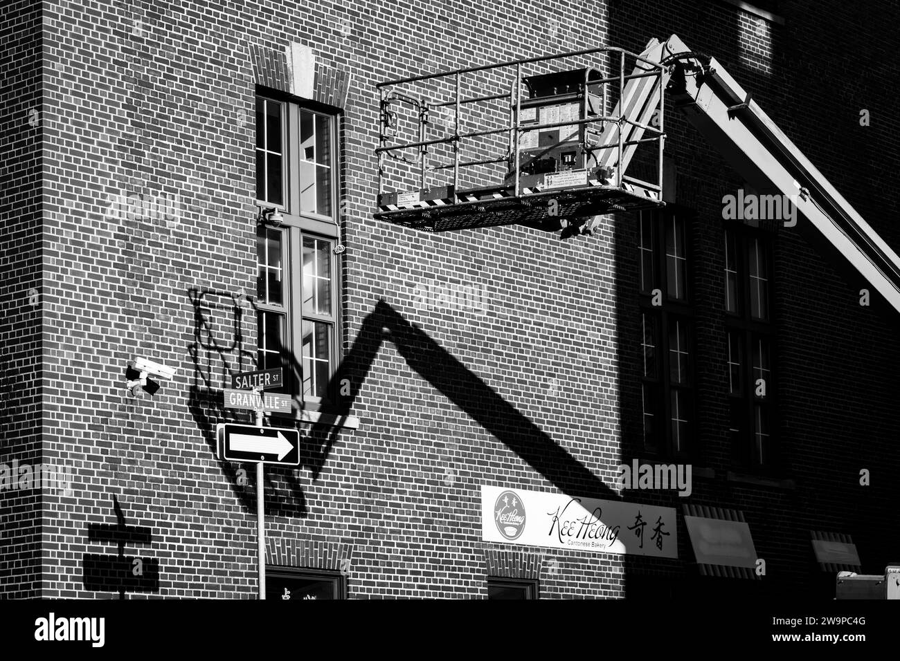Hydraulic work platform casts a shadow on the side of a brick building ...