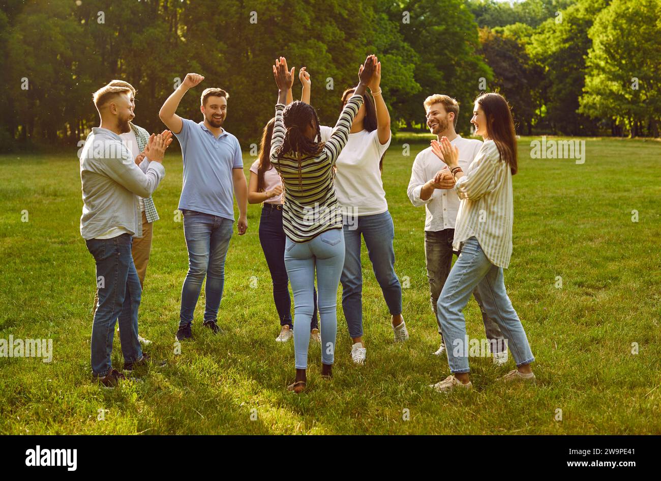 Group of happy young people having fun giving each other high five ...