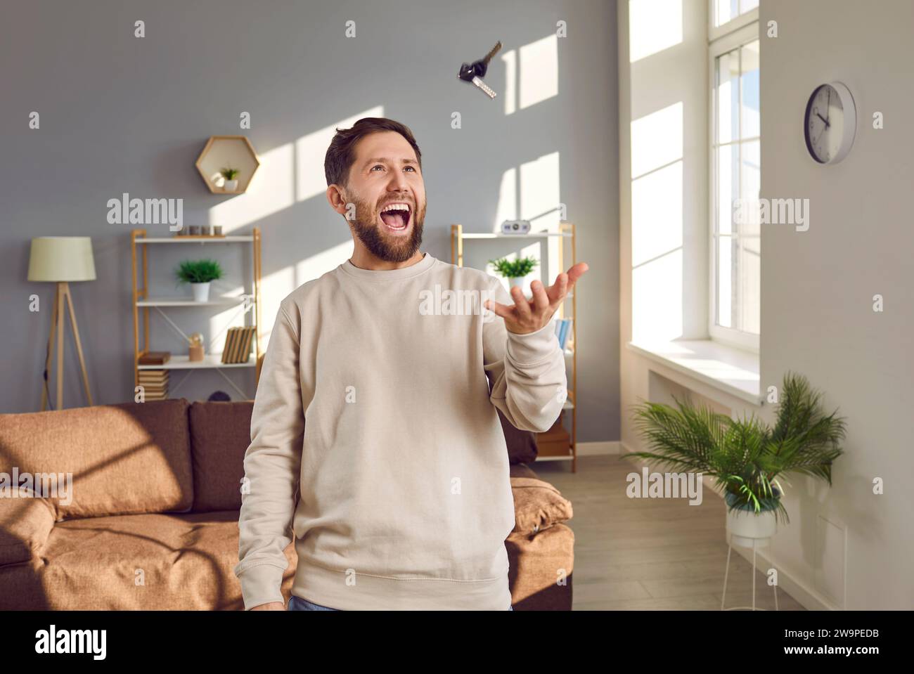 Happy, funny, excited man throwing key up in air in his newly bought ...
