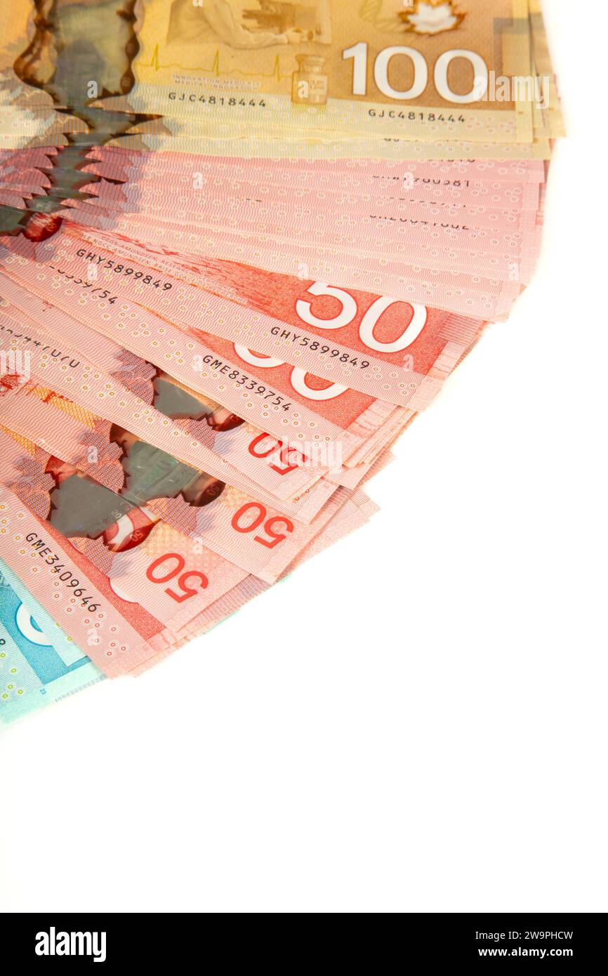A stack of candian bills of different denomination on a white ...