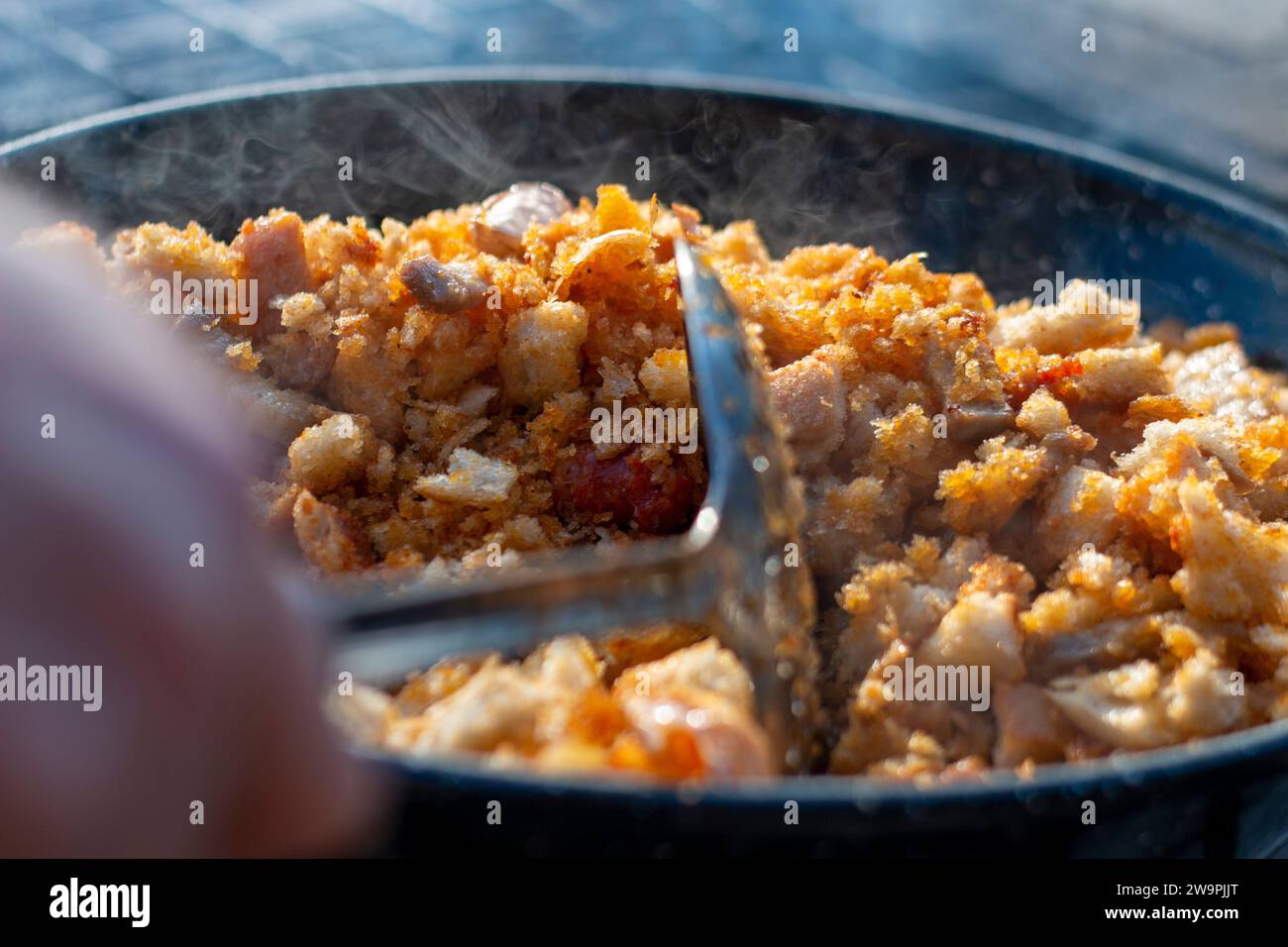 Cooking the typical Spanish dish of "Migas Castellanas" over a wood ...