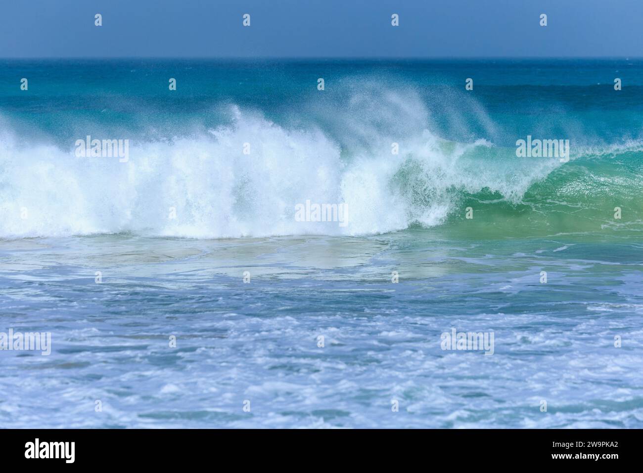 A large wave with turquoise water and white foam approaches on a windy ...