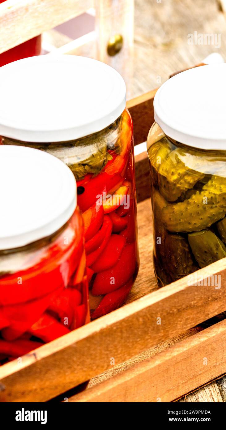 Wooden crate with glass jars with pickled red bell peppers and pickled ...