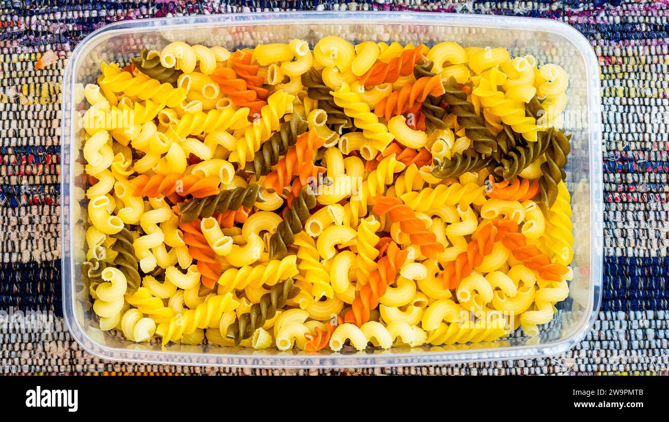 Tricolore fusilli, raw Italian pasta in plastic container, close up ...