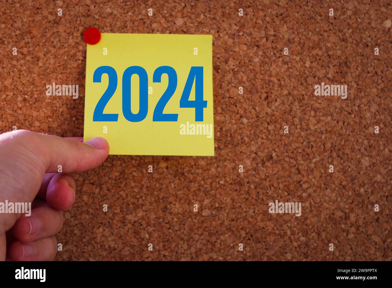 a man's hand pulling out a sticky note. year change from 2023 to 2024 ...