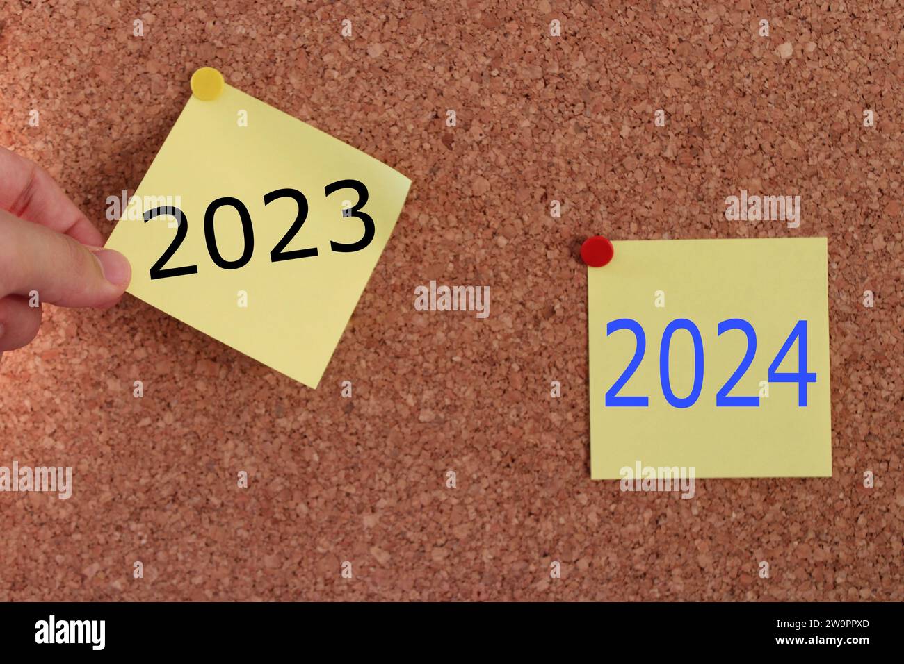 a man's hand pulling out a sticky note. year change from 2023 to 2024 ...