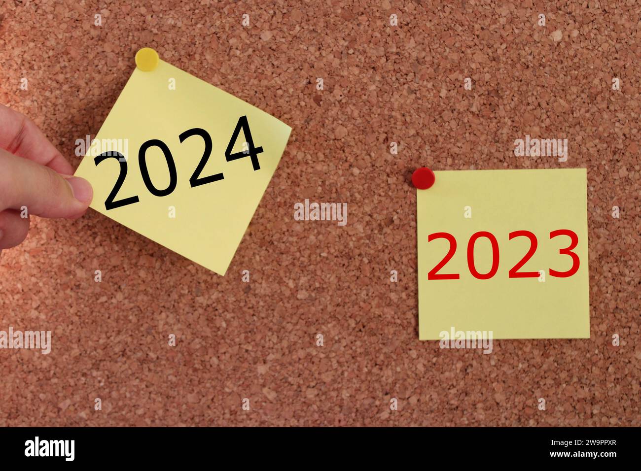 a man's hand pulling out a sticky note. year change from 2023 to 2024 ...