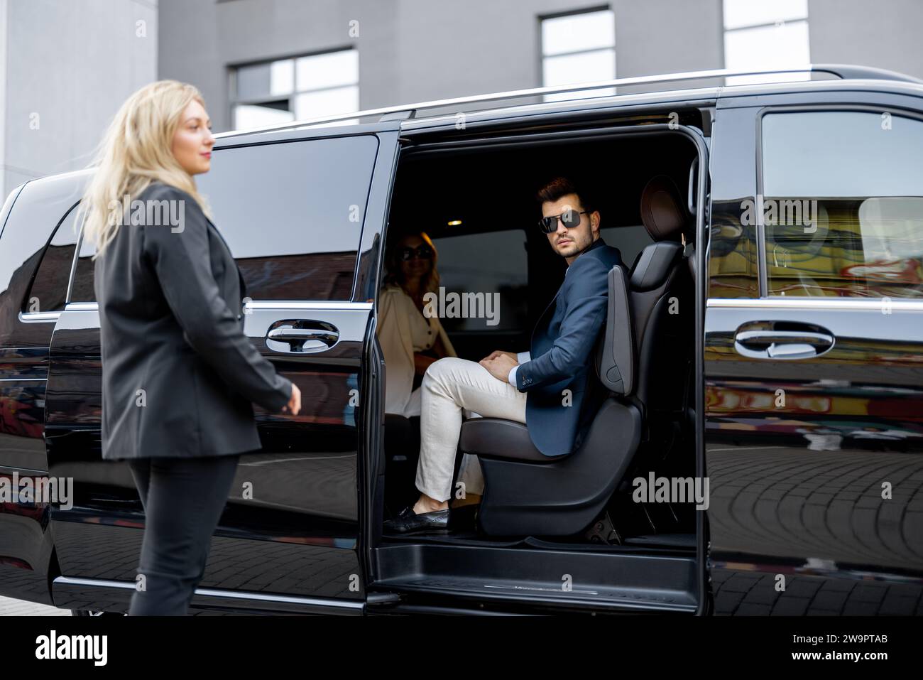 Female chauffeur helps a business people to get out of a vehicle Stock ...