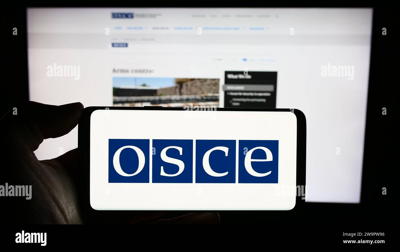 Person holding mobile phone with logo of Organization for Security and ...